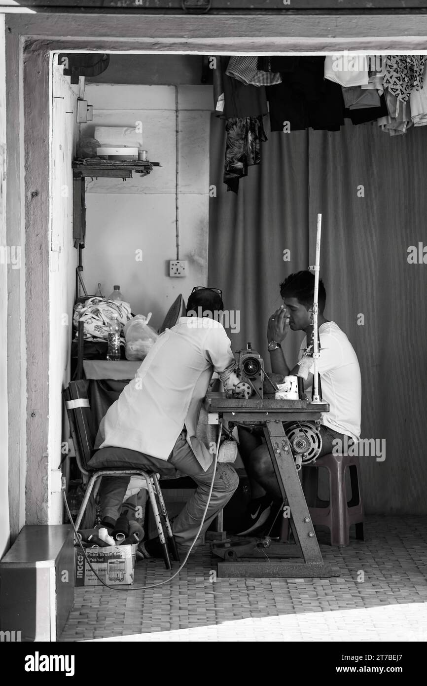 A traditional Indian tailor shop in black and white. A street scene ...