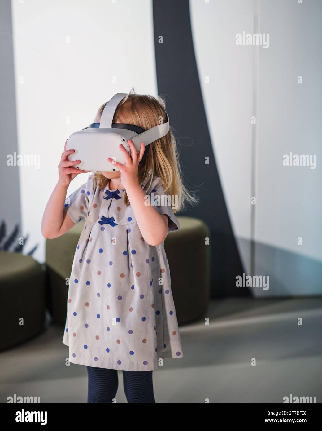 Adorable toddler girl with a virtual reality headset standing in a ...