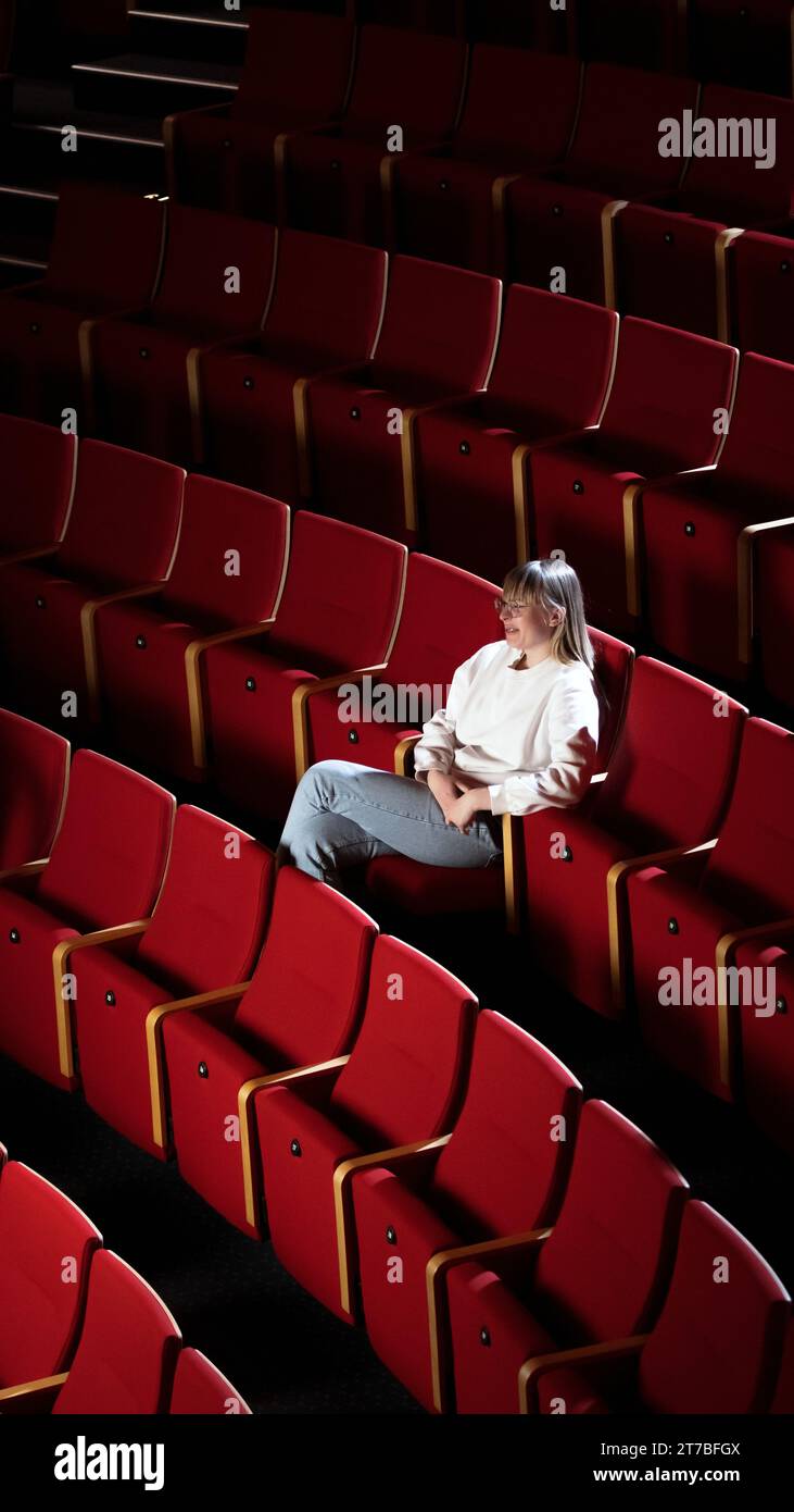 Young teenager female alone in cinema having fun watching a film in the ...