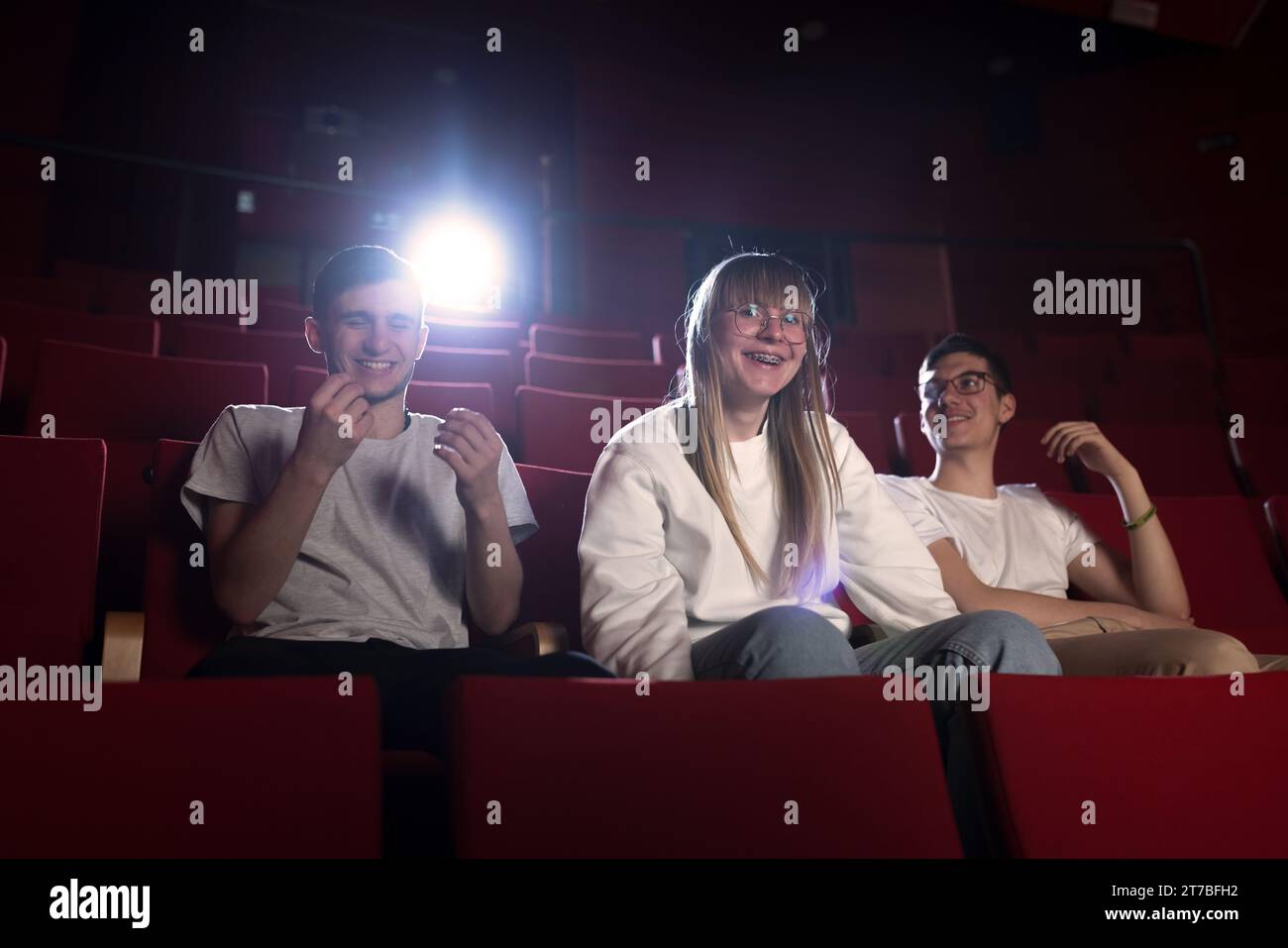Three friends in the cinema hall, a girl and two boys having fun ...