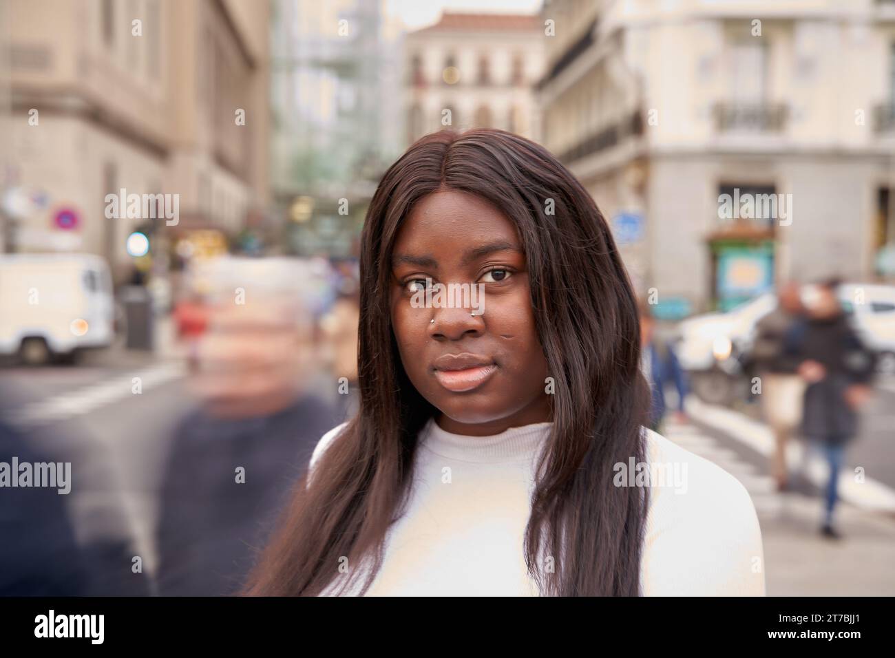 Portrait of african american girl looking at camera standing on pedestrian street by herself ...