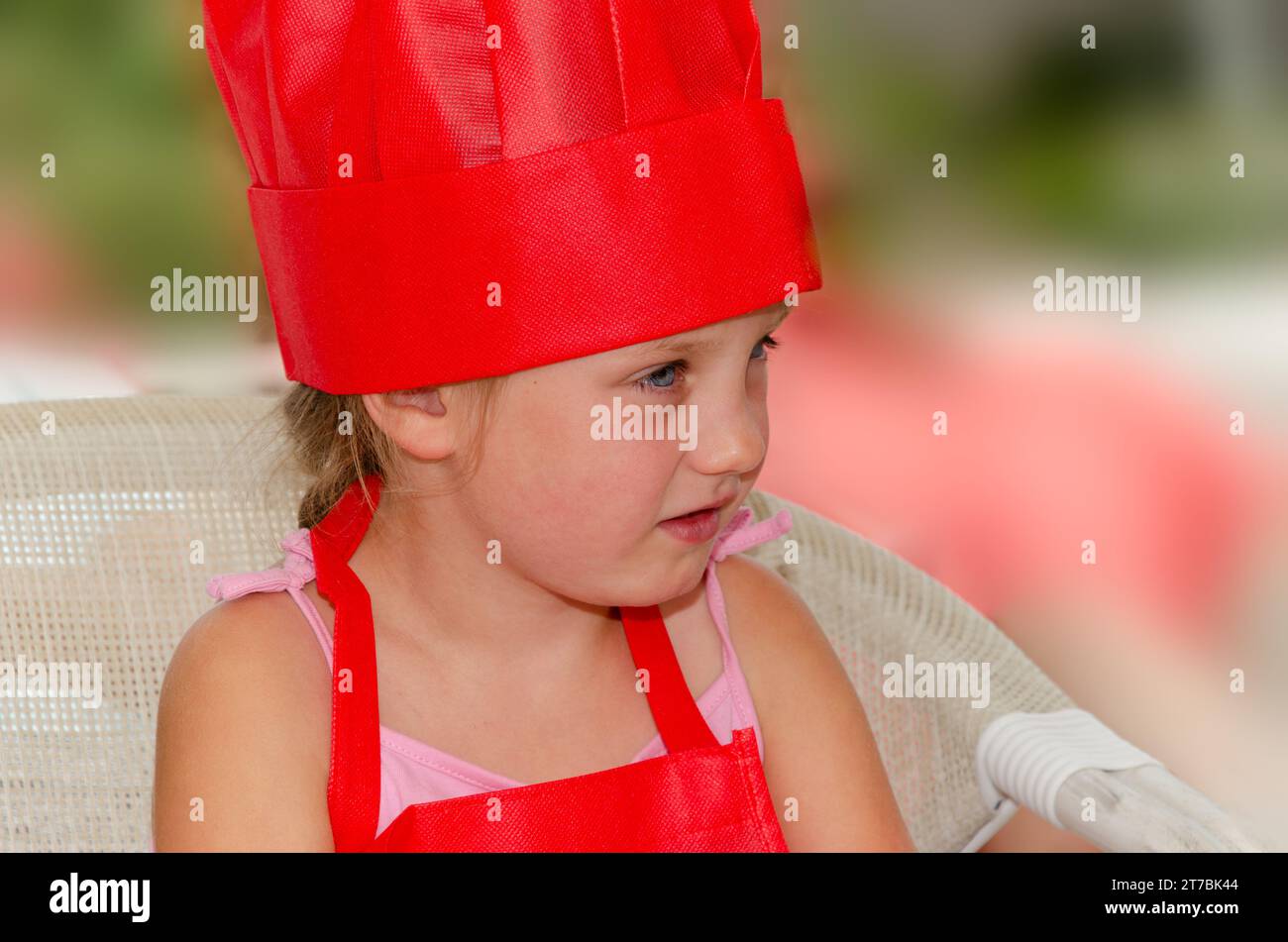 White girl 5 years old in red chef's hat and apron. Close-up of her ...