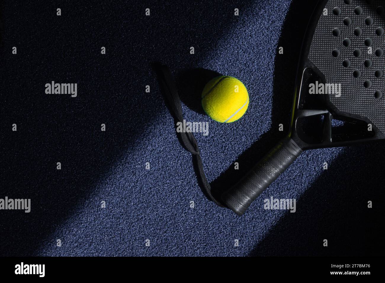 Black professional paddle tennis racket and ball with natural lighting ...