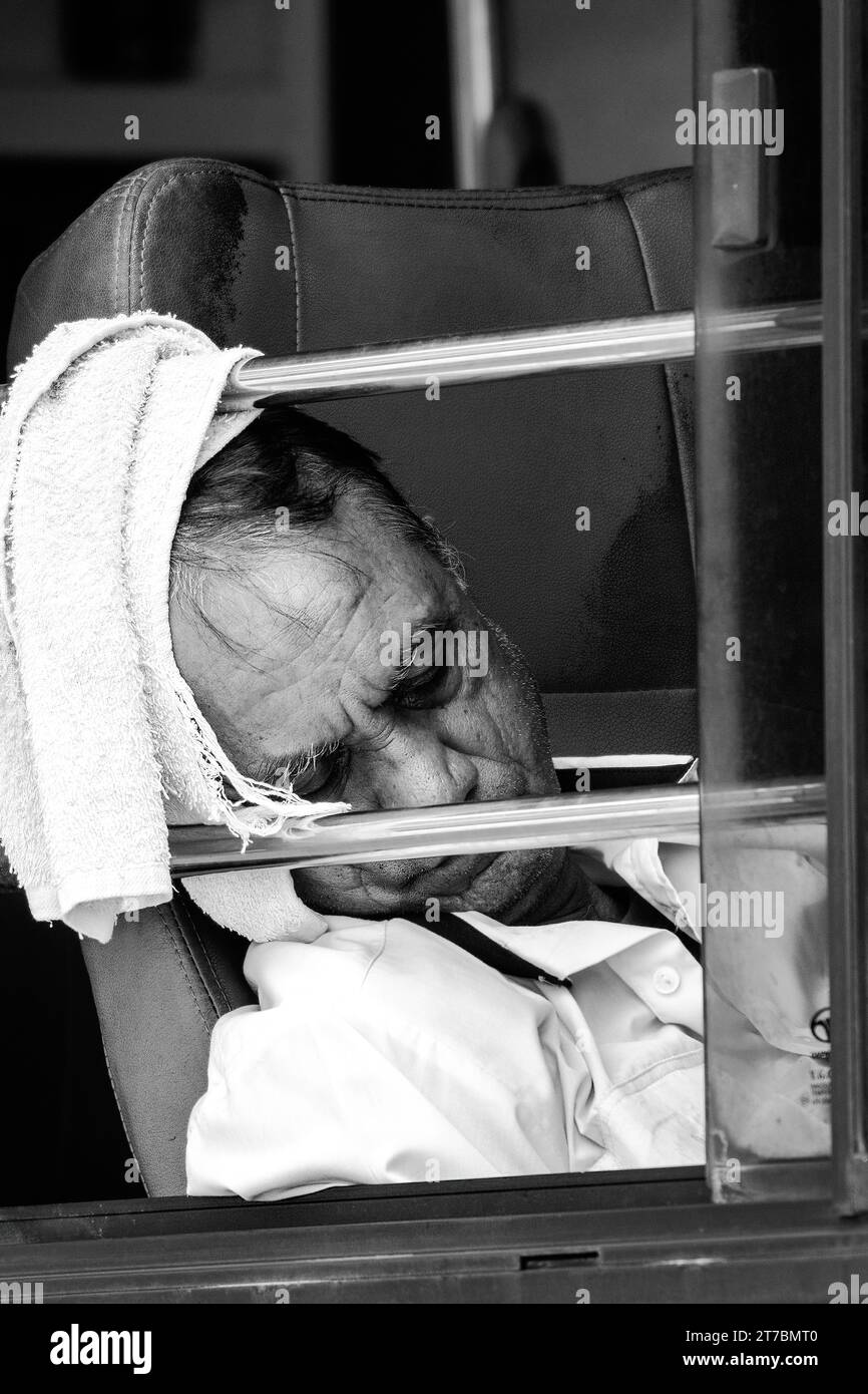 Black and white street portrait of an Indian bus driver having a nap in ...