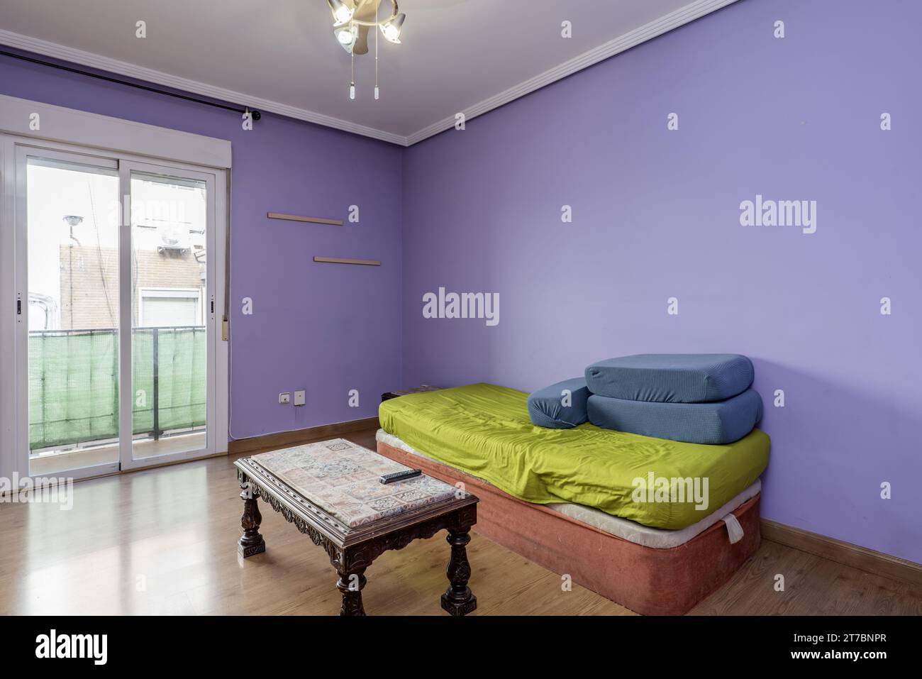 A small living room in a house with a coffee table and a messy bed ...