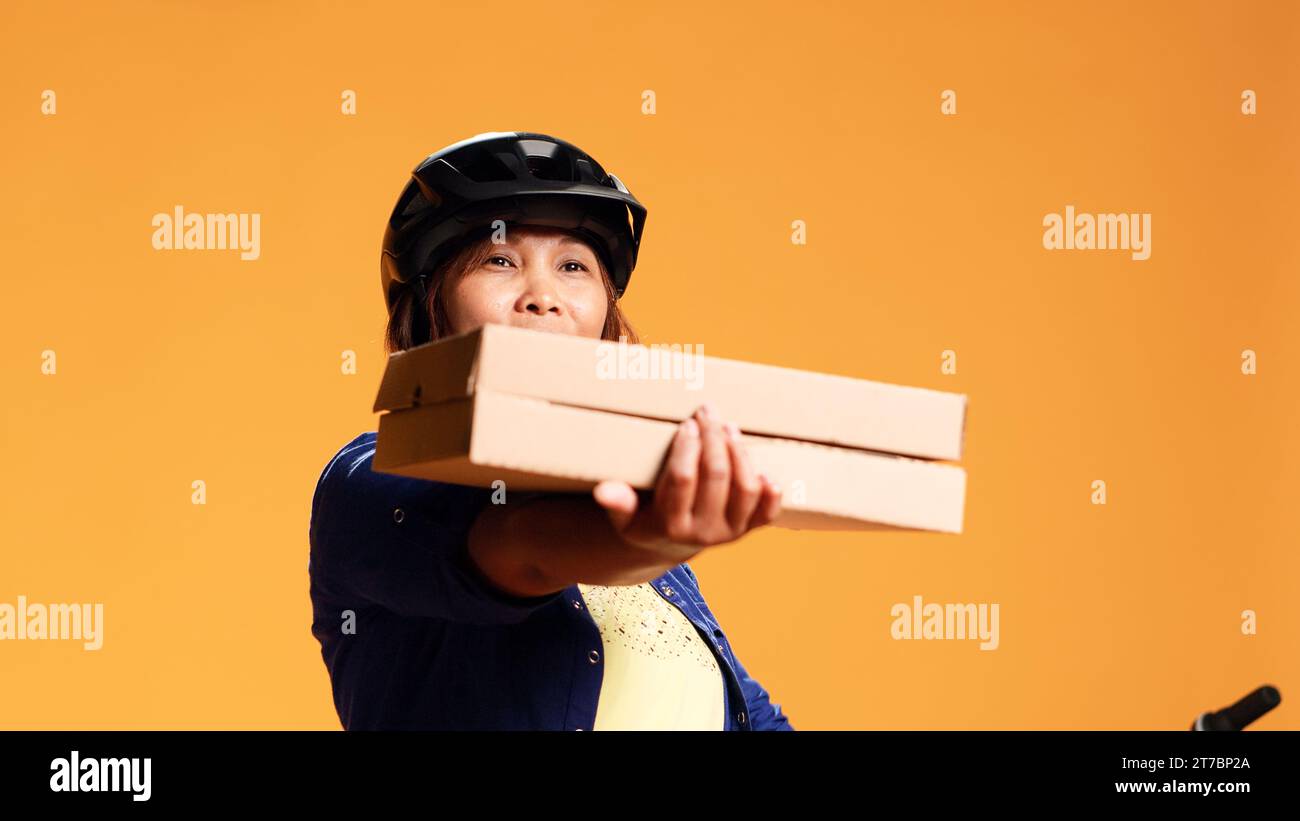 Hip level close up shot of cheerful courier looking at camera, showing ...