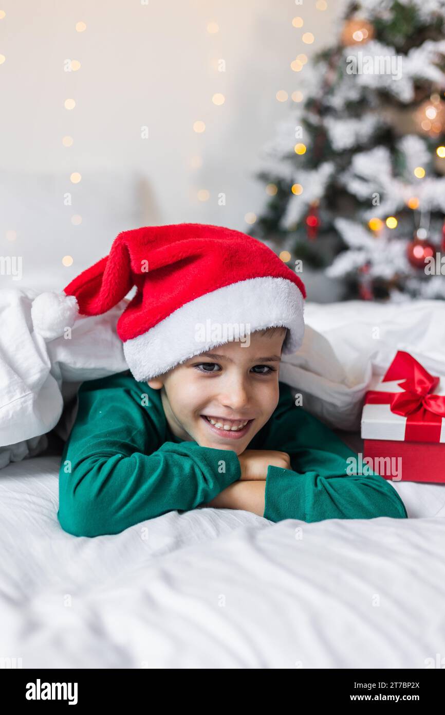Beautiful child boy santa hat resting in decorated home for Christmas, enjoying holidays at home ...