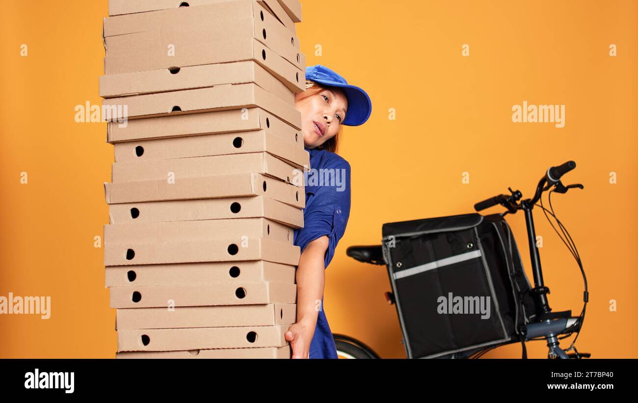 Tired courier burdened by huge pile of pizza, waiting for client to ...