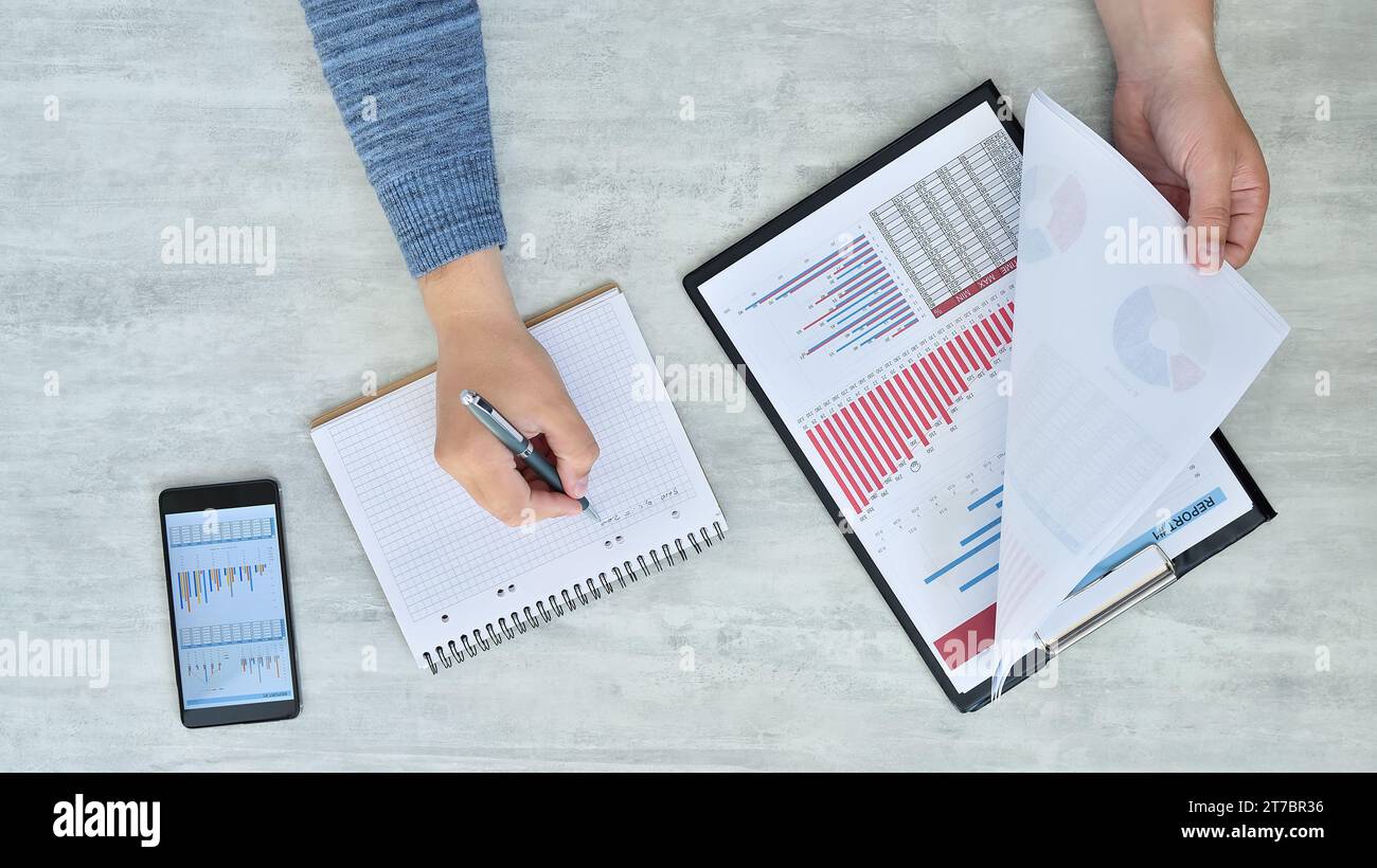 Top view of trader man checking profits and drawing data in note pad ...
