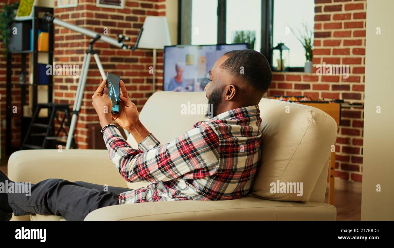 Excited african american man playing space shooting game on smartphone ...