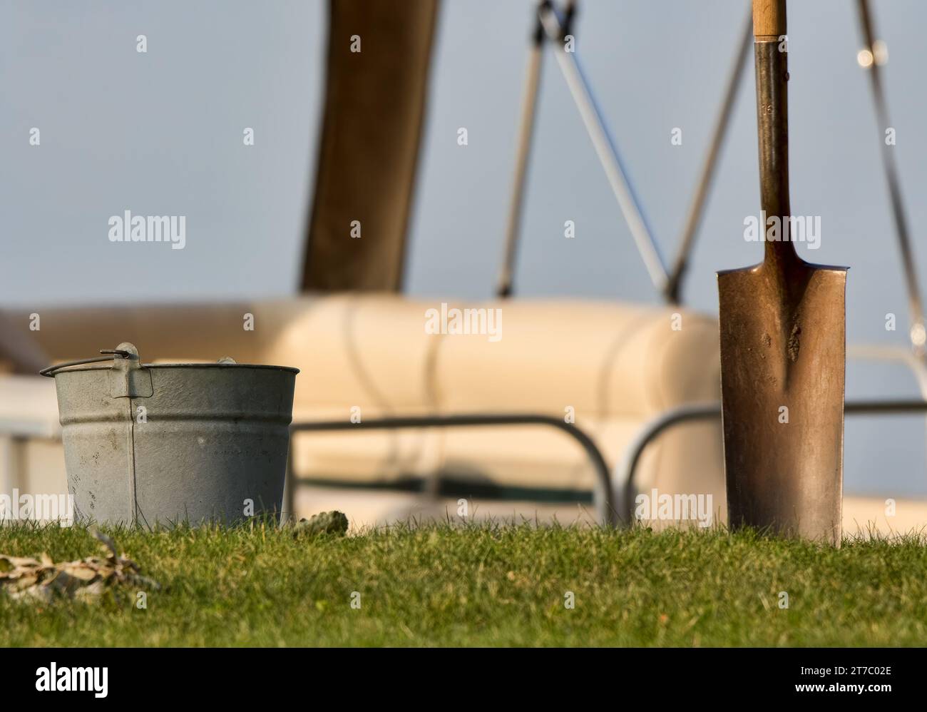 Bucket side by side with a spade shovel with pontoon and lake as ...