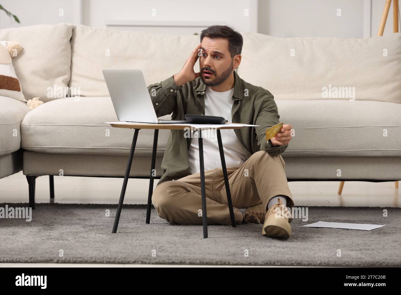 Confused man with calculator and credit card using laptop for planning ...
