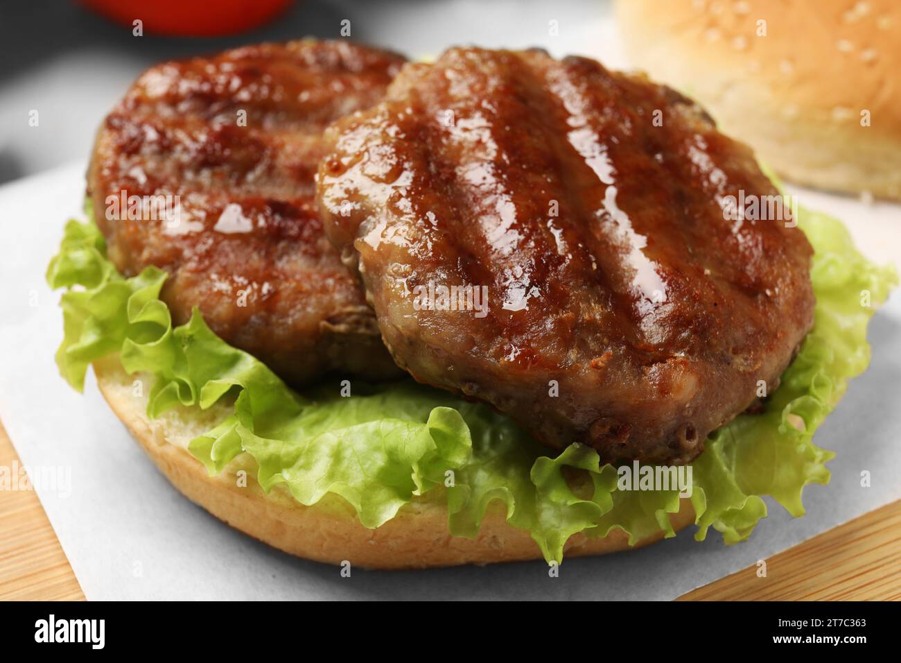 Delicious fried patties, lettuce and bun on board, closeup. Making ...