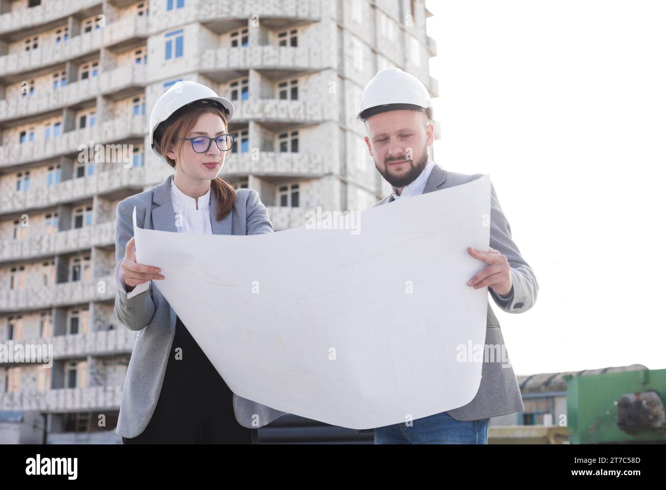 Two professional architect holding blueprint looking it near ...