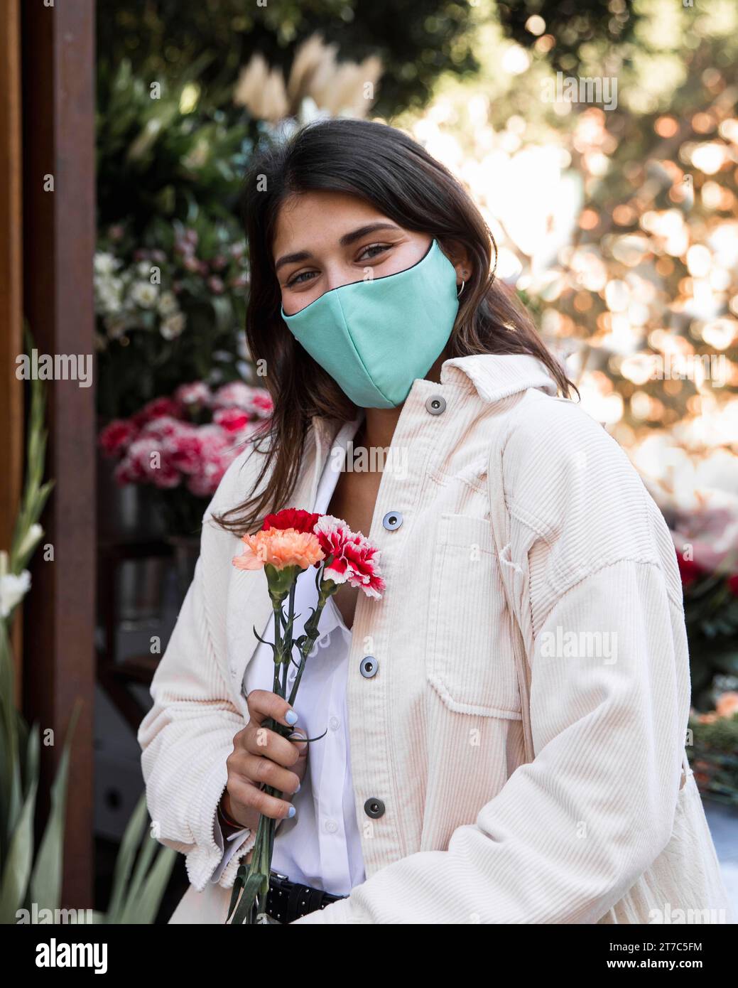 Woman with face mask posing outdoors with flowers Stock Photo - Alamy