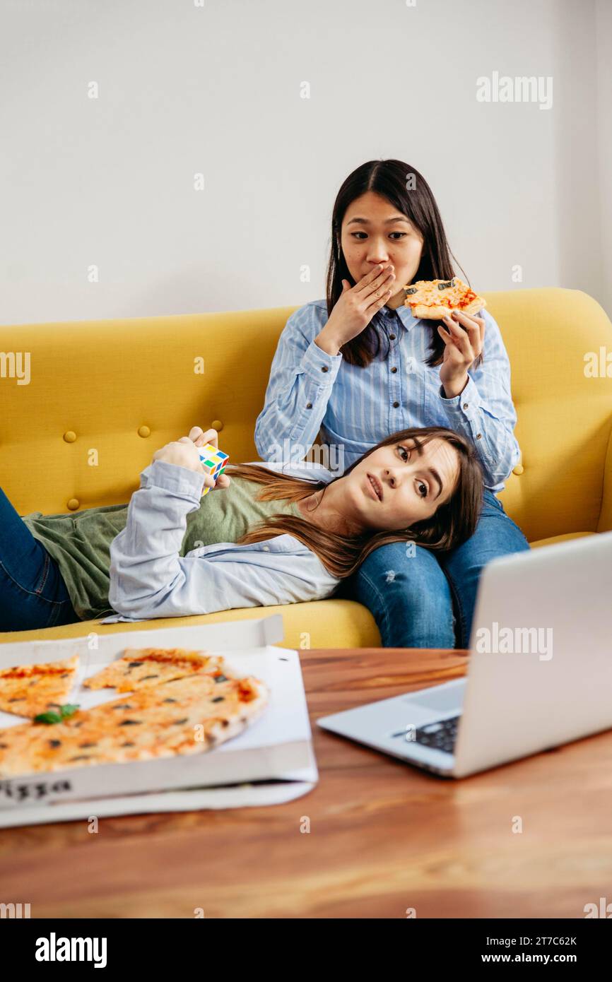 Chilling girls watching movie eating pizza Stock Photo - Alamy