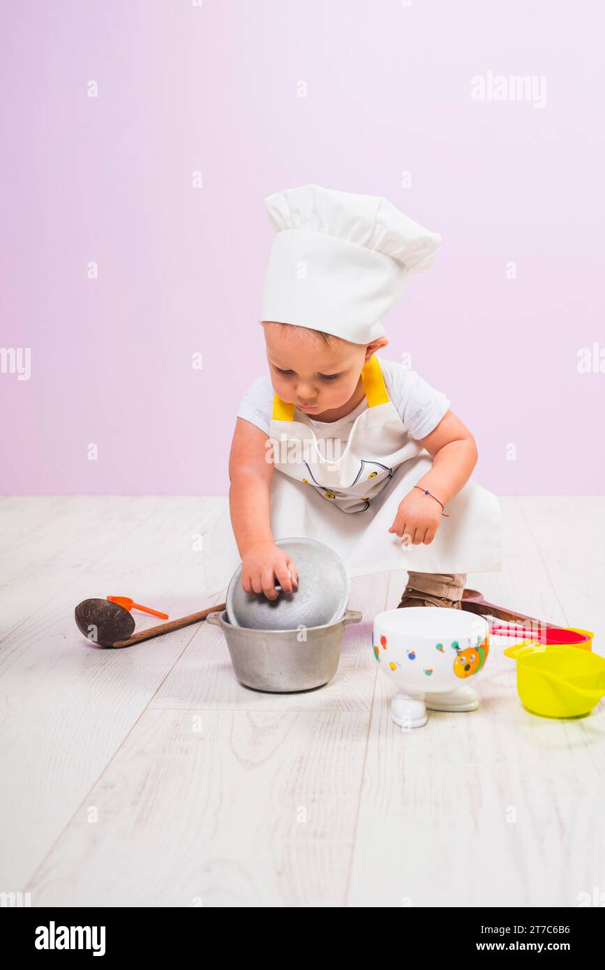 Cook child sitting with kitchen utensils floor Stock Photo - Alamy