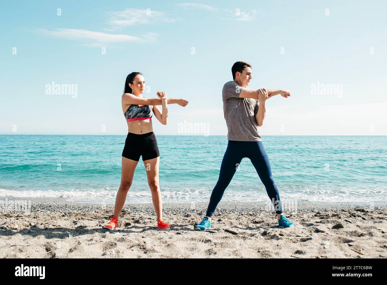 Couple stretching beach Stock Photo - Alamy