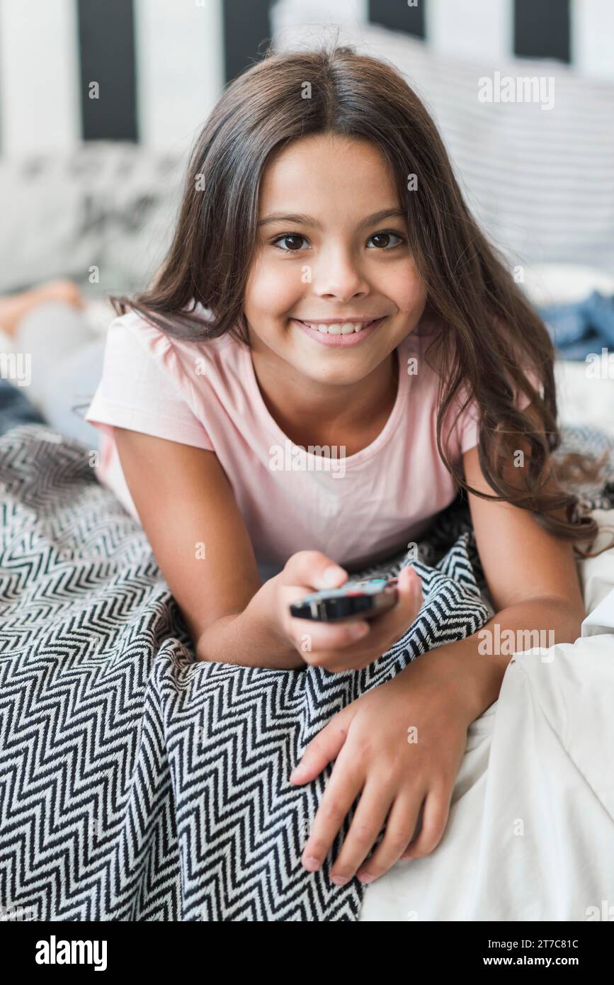 Smiling portrait girl lying bed using remote control Stock Photo - Alamy Smiling portrait girl lying bed using remote control Stock Photo - Alamy