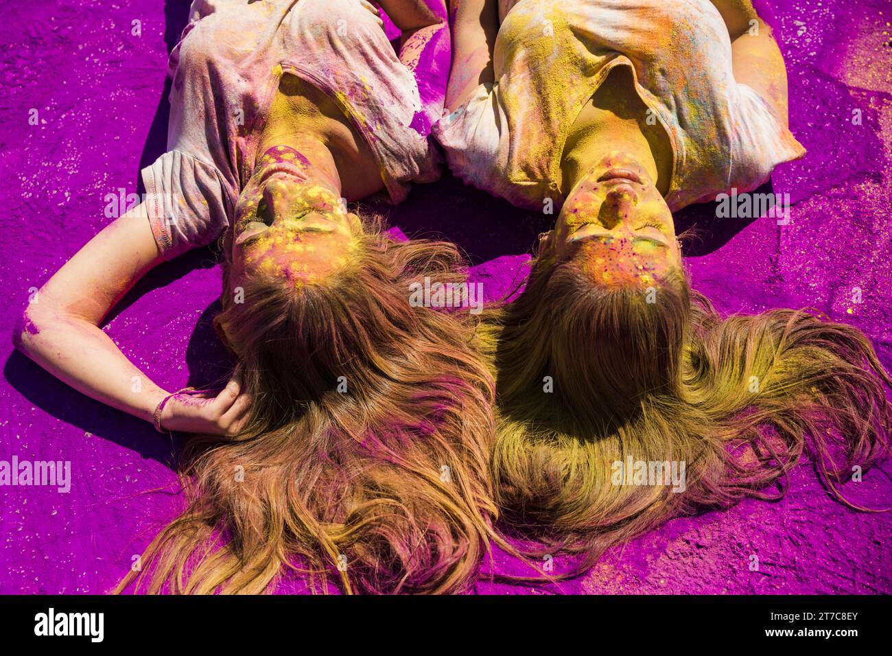 Two young women lying purple holi color powder Stock Photo - Alamy