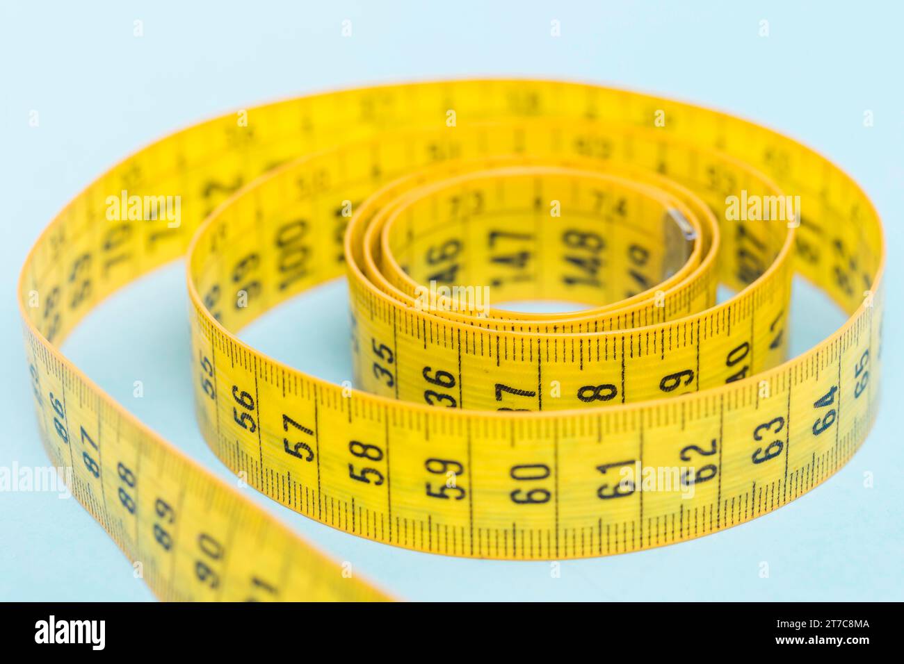 Yellow tape measure blue background Stock Photo - Alamy