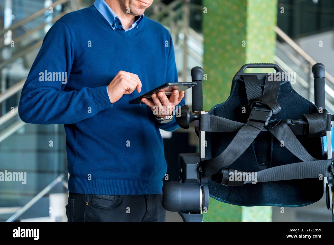 Unrecognizable computer engineer in mechanical exoskeleton looking at ...