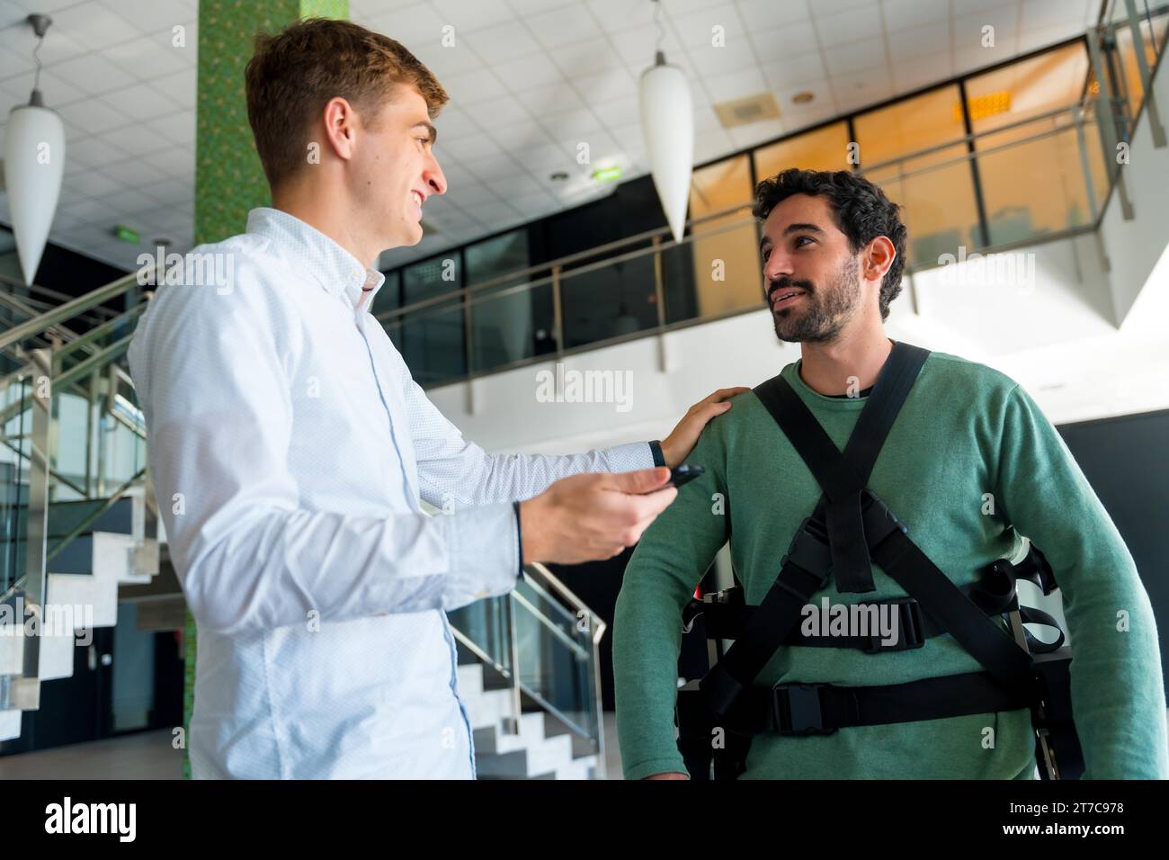Mechanical exoskeleton, physiotherapist talking to disabled person with ...