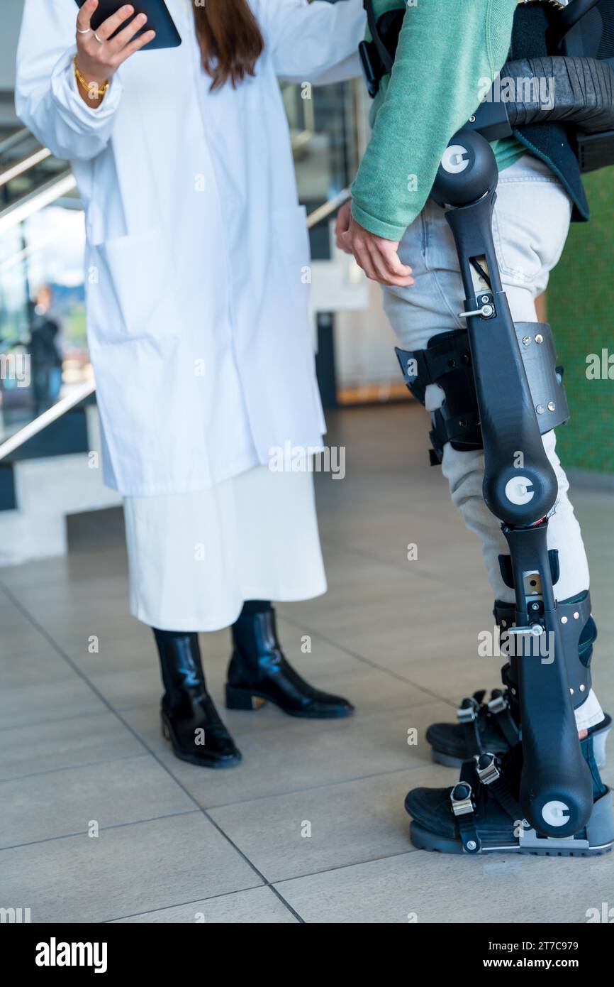 Mechanical exoskeleton, female physiotherapist doctor talking and ...