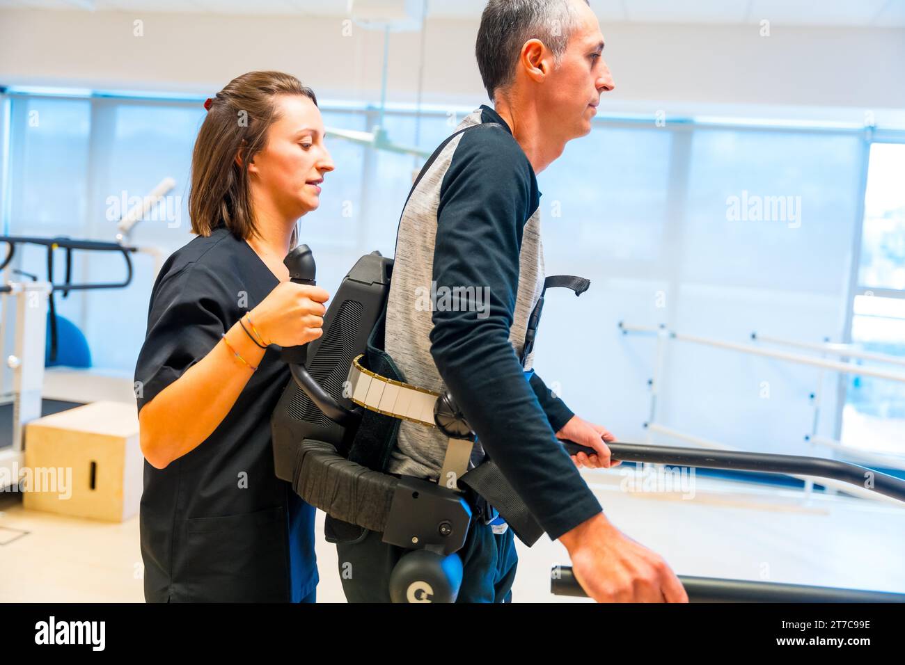 Mechanical exoskeleton. Female physiotherapy medical assistant helping disabled person with ...