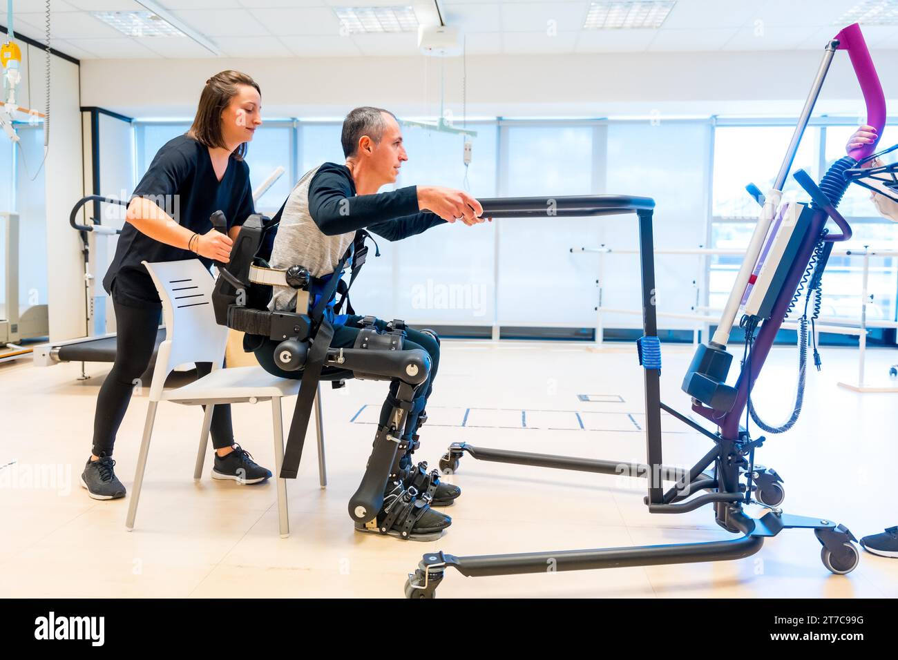 Mechanical exoskeleton. Physiotherapy assistant lifting disabled person ...