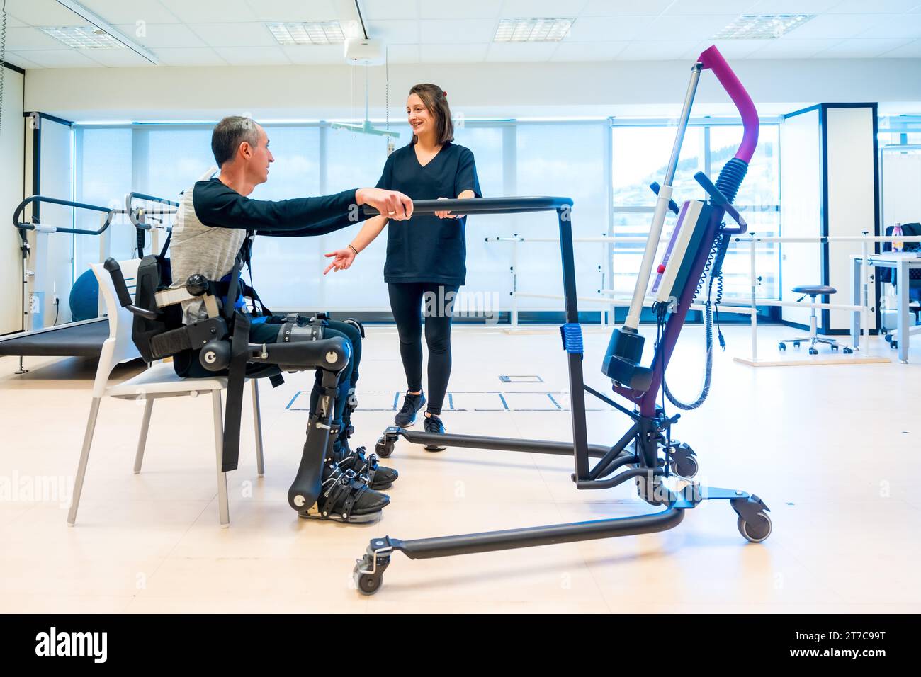 Mechanical exoskeleton. Physiotherapy assistant lifting disabled person ...