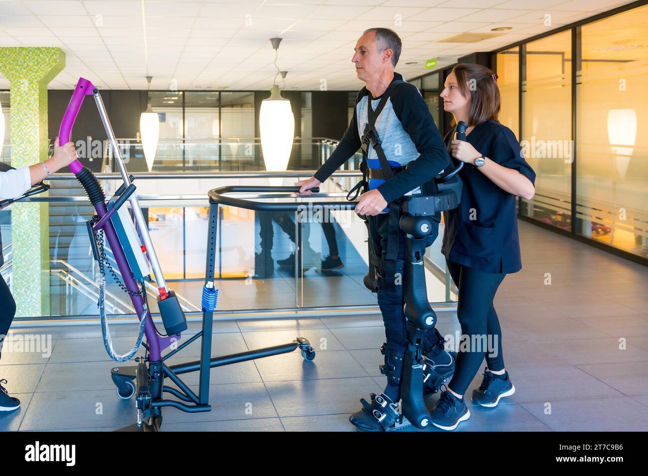 Mechanical exoskeleton. Female physiotherapy doctor helping disabled ...