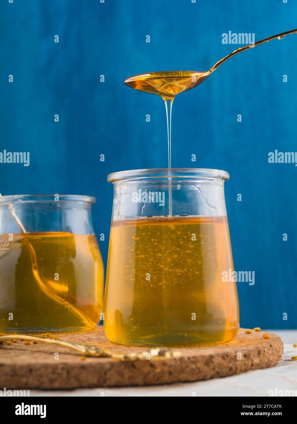 Fresh honey dripping glass pot cork coasters against blue background ...