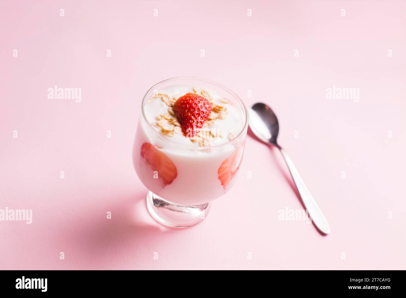 Glass oat granola with yogurt fresh strawberries spoon pink background Stock Photo - Alamy