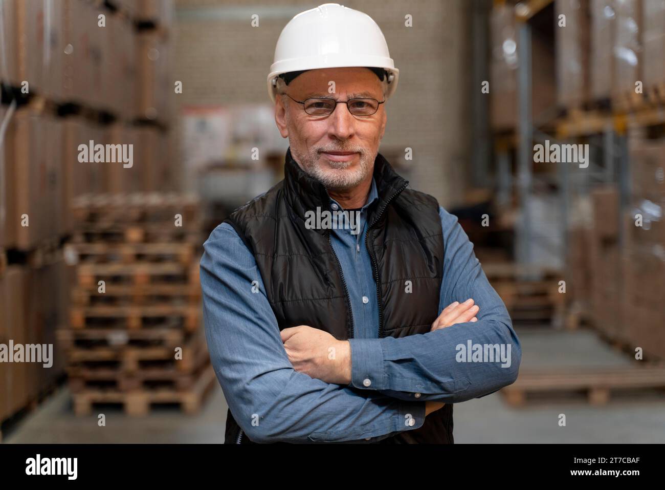 Man with arms crossed working warehouse Stock Photo - Alamy