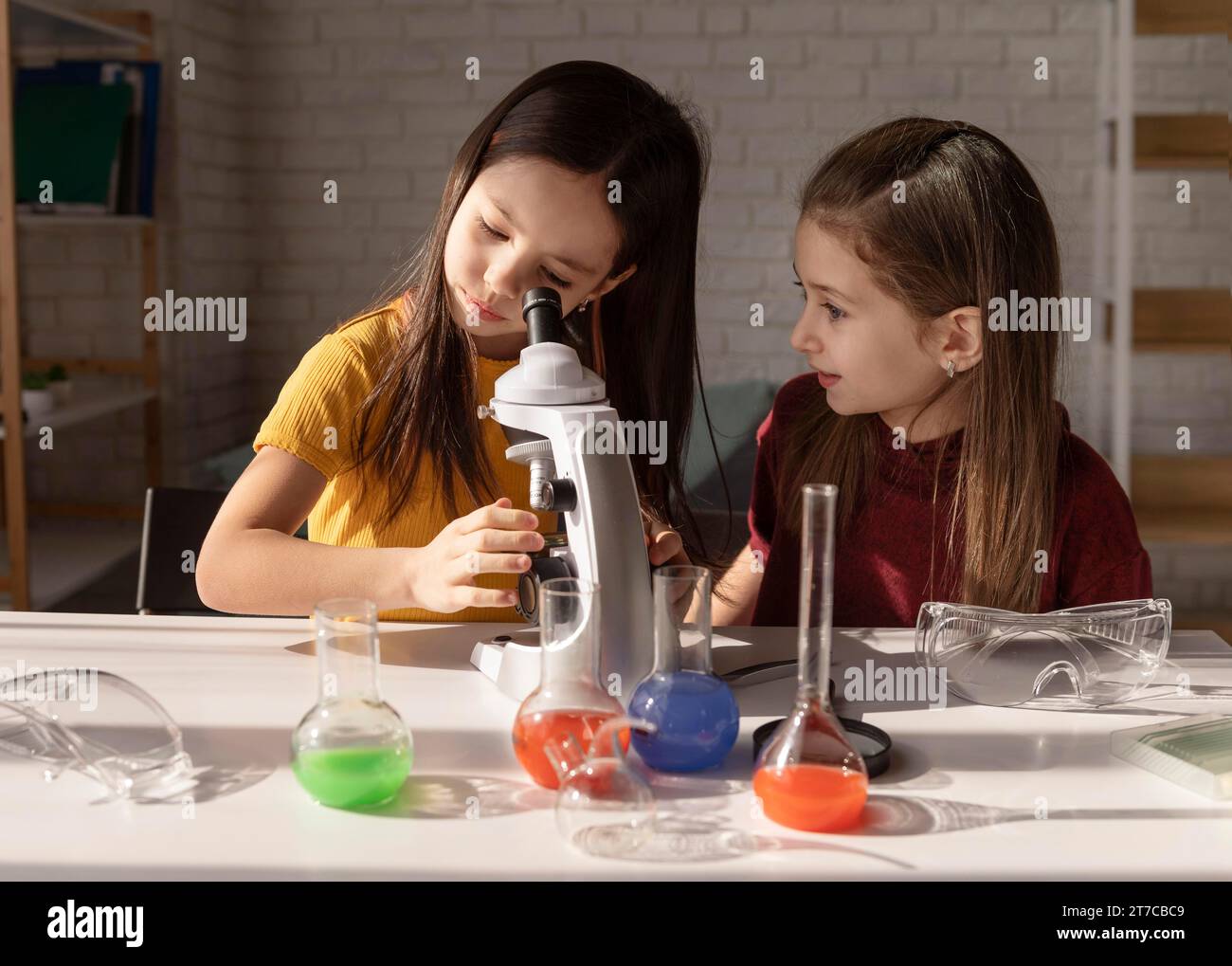 Medium shot girl looking through microscope Stock Photo - Alamy