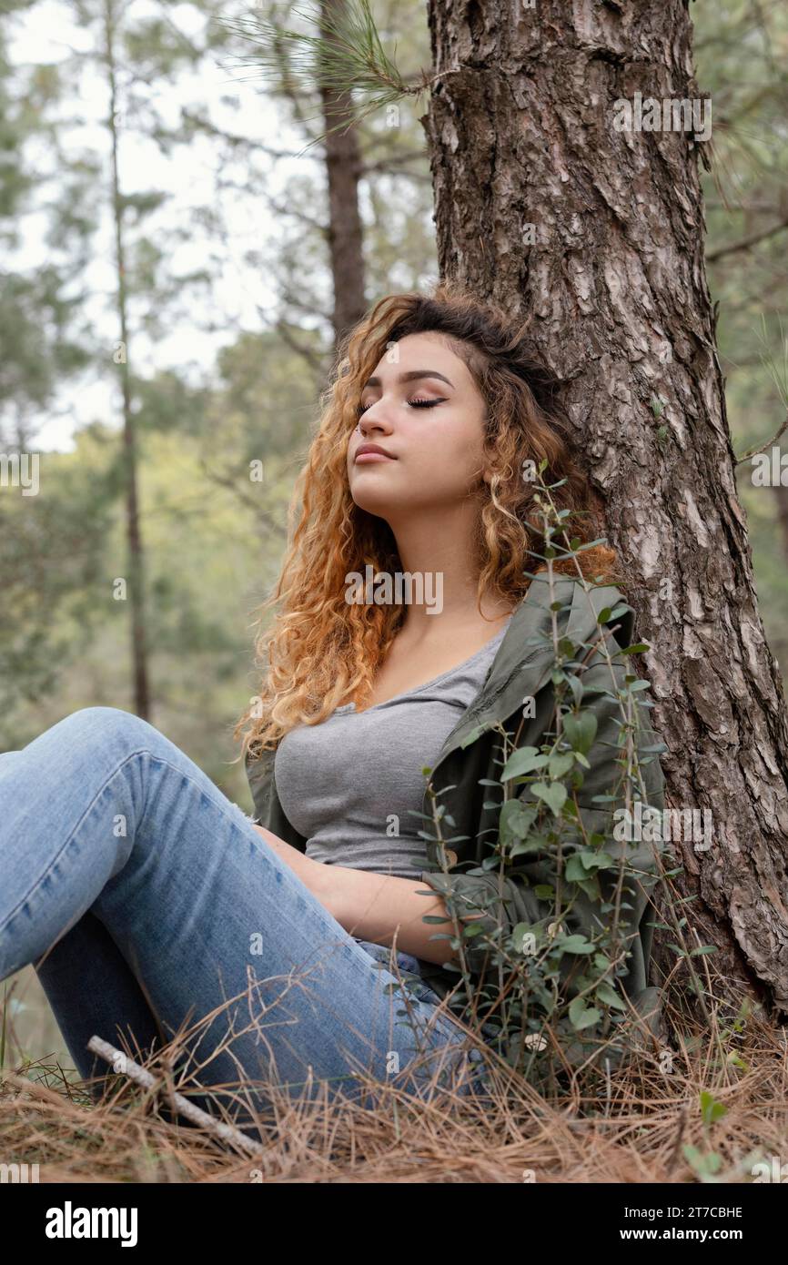Medium shot woman sitting near tree Stock Photo - Alamy