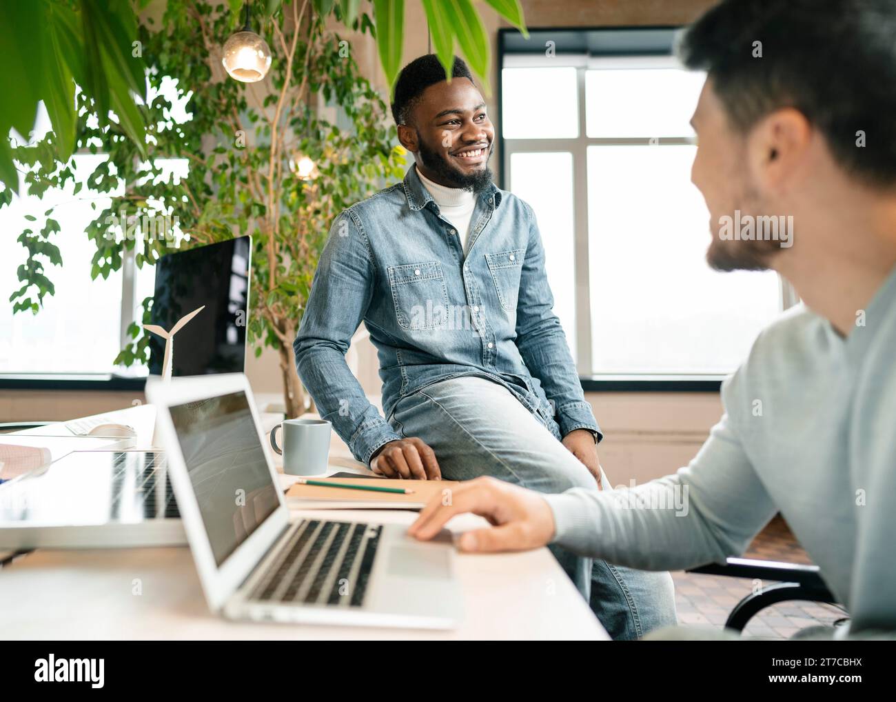 Men discussing project desk Stock Photo - Alamy