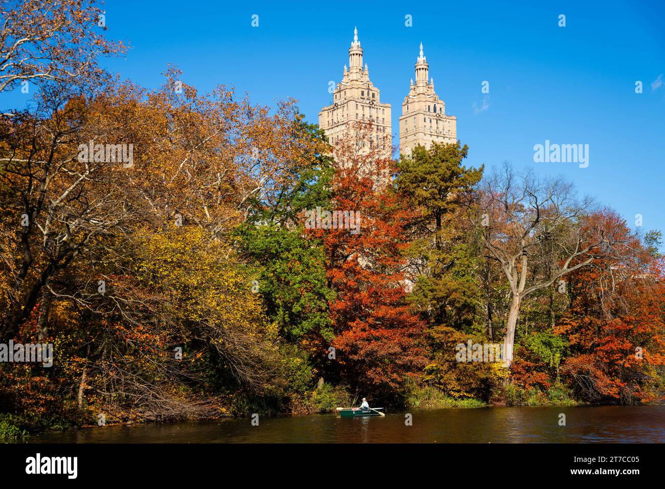 Skyscrapers loom above the multicolored trees of autumn in Central Park ...