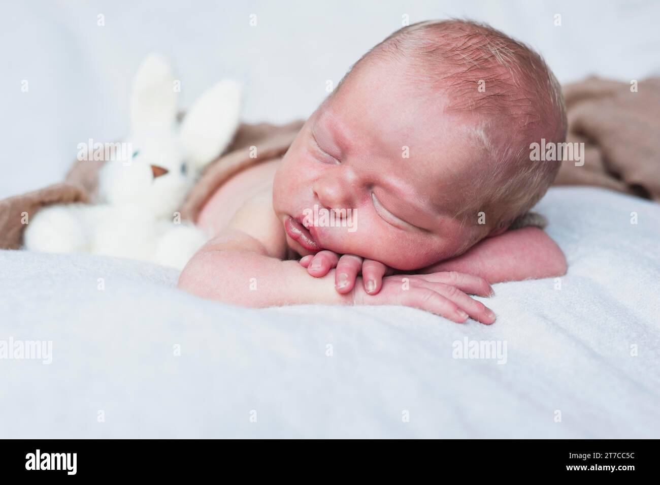 Sleepy baby with toy rabbit Stock Photo - Alamy