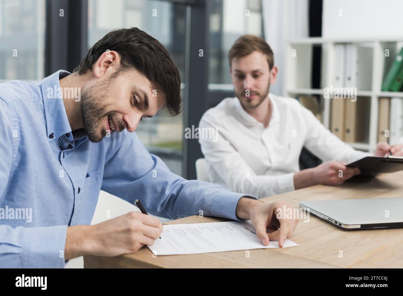 Side view smiley man signing work contract Stock Photo - Alamy