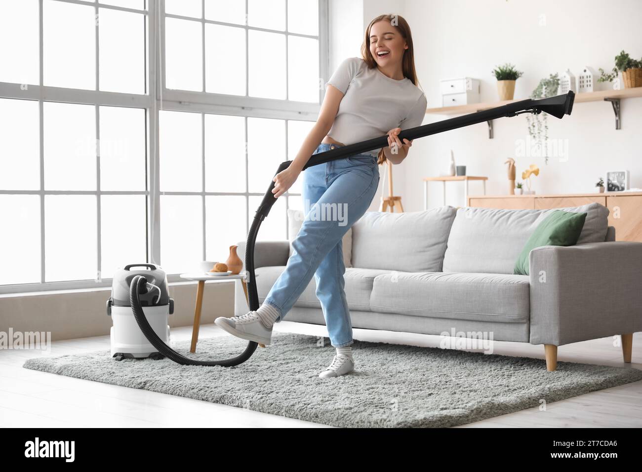 Young woman with vacuum cleaner singing at home Stock Photo - Alamy