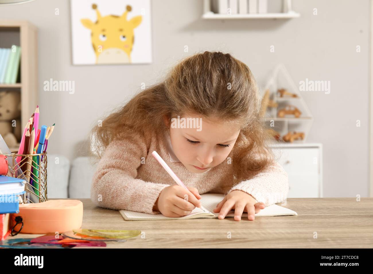 Cute little girl writing in copybook at home Stock Photo - Alamy