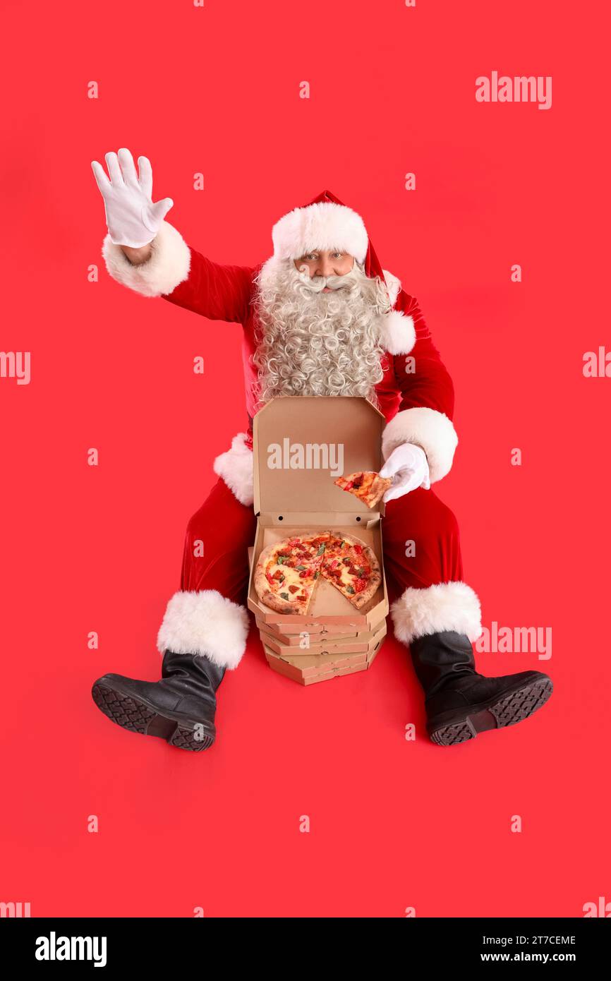 Santa Claus with tasty pizza sitting on red background Stock Photo - Alamy