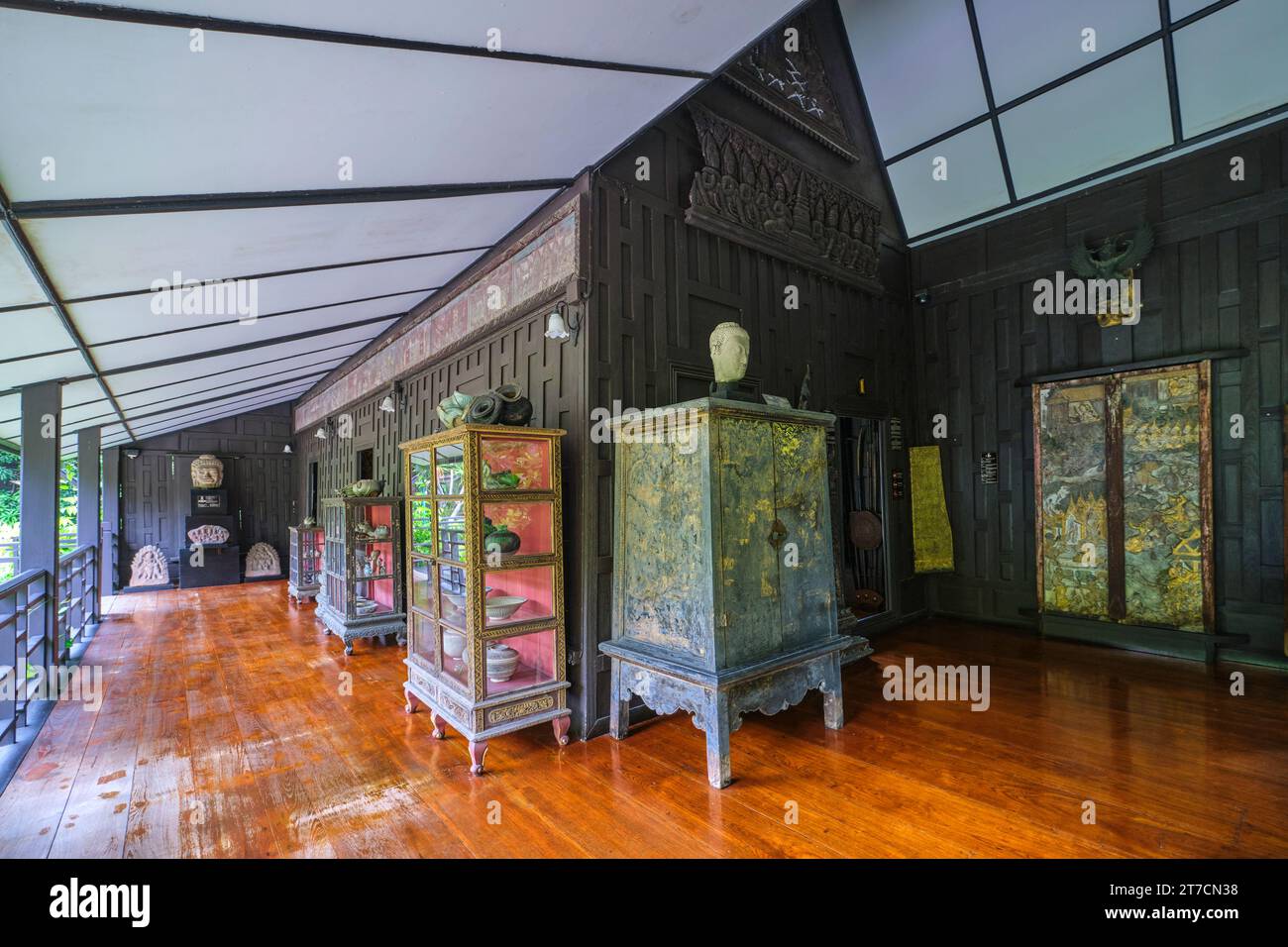 Various painted display cases full of old objects, on a wide veranda of ...