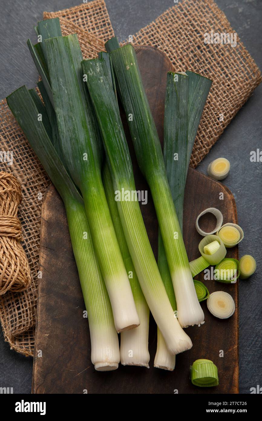 Whole and cut fresh leeks on a dark background, vegetarian food ...