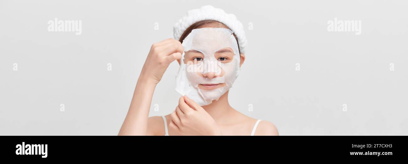 Happy young removing from face skincare hydrating sheet mask with ...