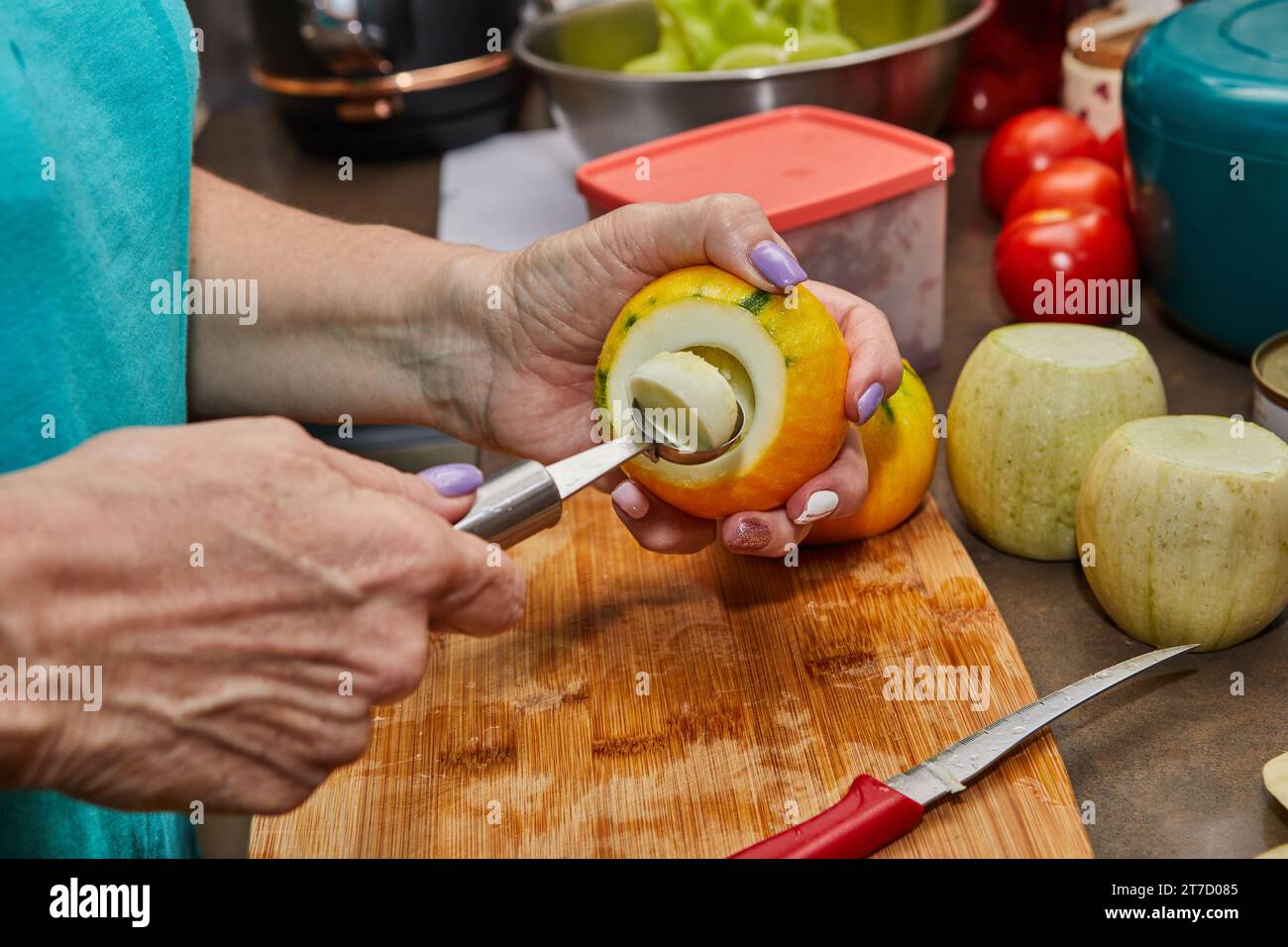 Chef cuts out the inside of zucchini for stuffing in home kitchen Stock ...