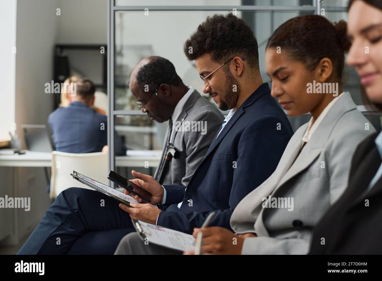 Group of people sitting in a row and filling documents, they applying ... Group of people sitting in a row and filling documents, they applying ...