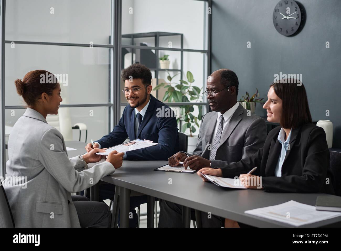 Young woman giving her documents for visa during her interview with ...